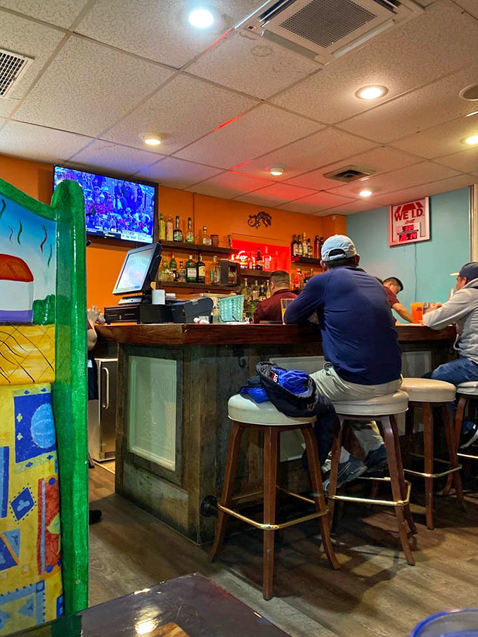 A cozy bar corner where sports on TV and tequila on shelves create that perfect "neighborhood watering hole with a Mexican twist" vibe.