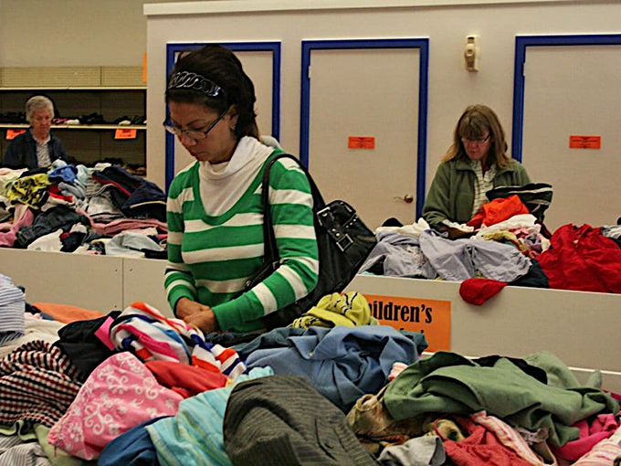 Dedicated shoppers sift through colorful children's clothing with the focus of archaeologists, unearthing tiny treasures one garment at a time.