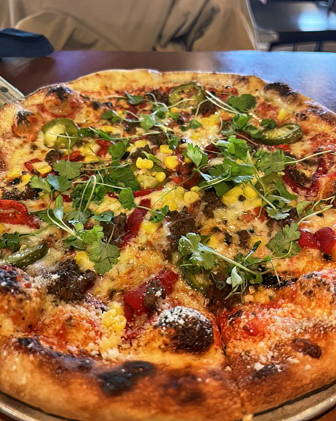 The Spicy Yuma pizza showcases a carnival of colors and textures—where corn, peppers, and herbs create a fiesta that your taste buds are definitely invited to.