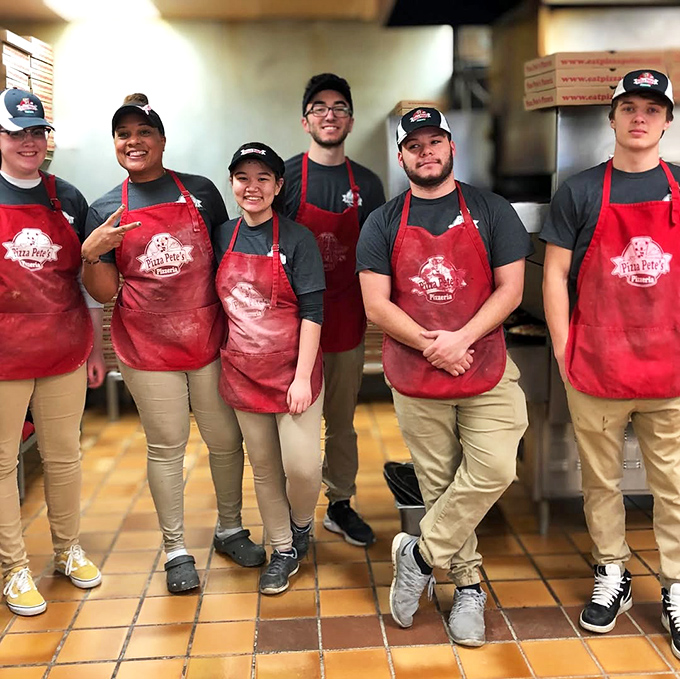 The smiling team behind the pizza magic, sporting those signature red aprons. These are the pizza artisans who transform simple ingredients into Erie delights.