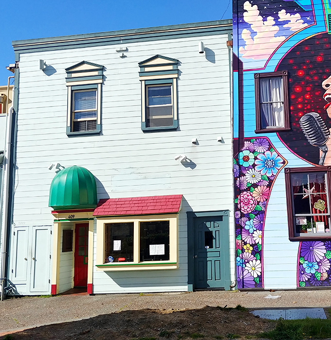 This unassuming storefront with vibrant mural neighbor shows Eureka's blend of practical affordability alongside artistic expression.