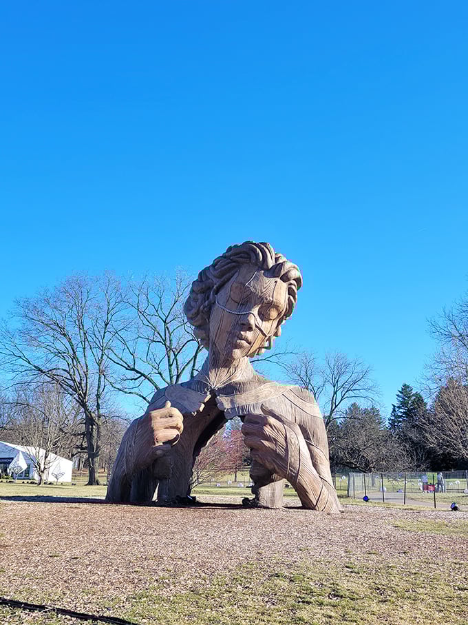 Winter reveals the sculpture's true character, with bare branches framing this wooden visage emerging from the earth like a slumbering forest deity.