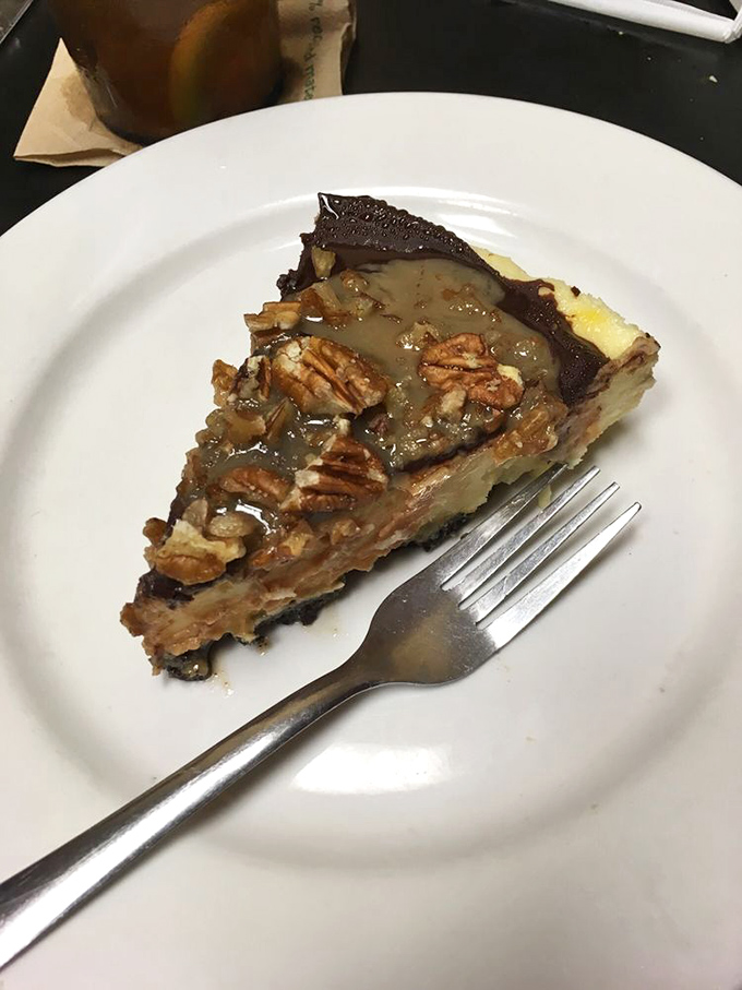 A slice of turtle cheesecake that makes you wonder if dessert should actually be the main course, with pecans standing guard over caramel treasure.