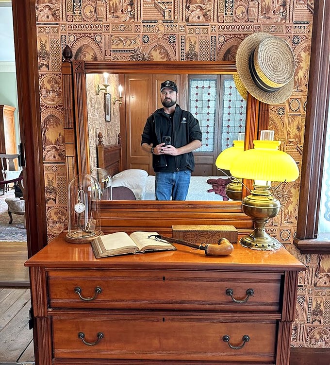 The reflection captures both the visitor and the elaborate Victorian furnishings, creating a time-bending moment where past meets present.