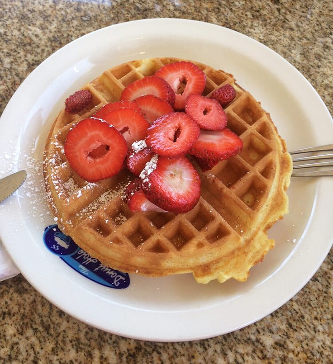 A waffle that's achieved golden perfection, topped with strawberries so red they could make Snow White jealous all over again.