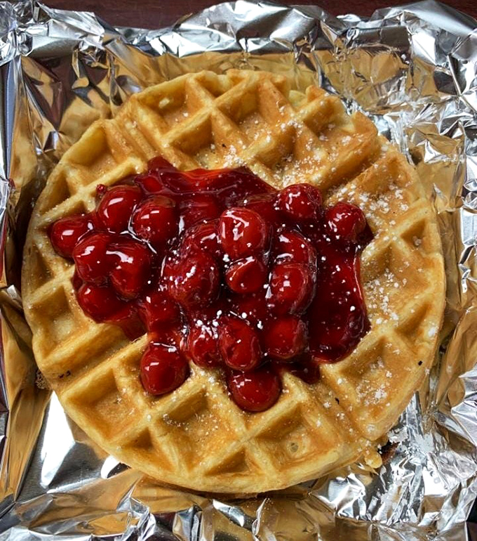 A waffle crowned with cherry royalty—the perfect balance of crispy exterior, fluffy interior, and sweet-tart topping that makes breakfast feel like dessert.