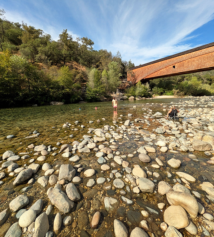 The South Yuba River's clear waters and smooth stones create nature's perfect soundtrack beneath this historic wooden sentinel.