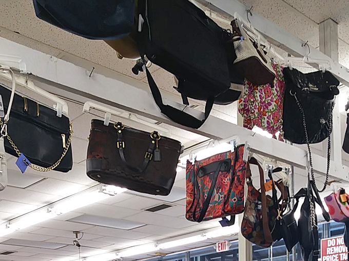 Handbags suspended from the ceiling like colorful stalactites in a retail cave. That floral tote probably carried someone's beach essentials in a previous life.