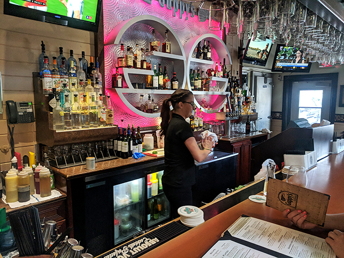 The bar at Guppy's glows with pink accent lighting, creating the perfect backdrop for crafting cocktails that taste like Florida sunshine in a glass.