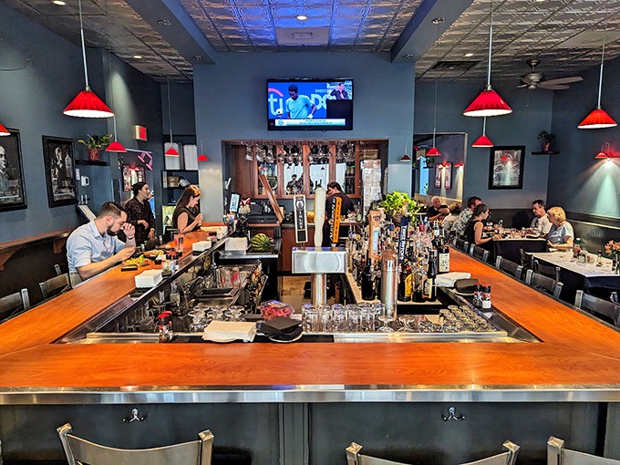 The bar where Hemingway would feel at home. Red pendant lights cast a glow that makes every drink look like a bestseller.