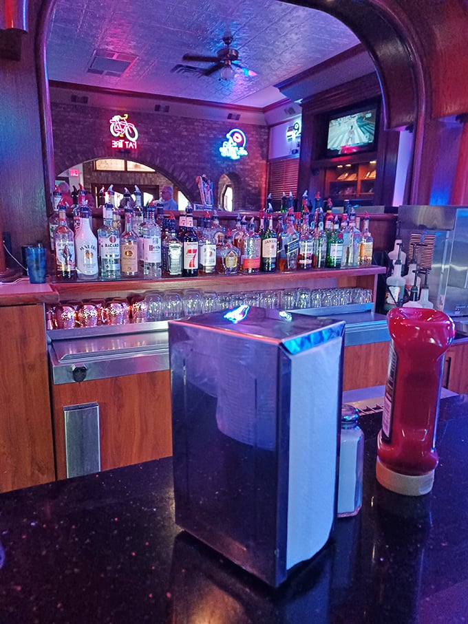 The bar gleams with bottles under neon light, promising liquid courage for those attempting to finish the Triple Bypass sandwich.