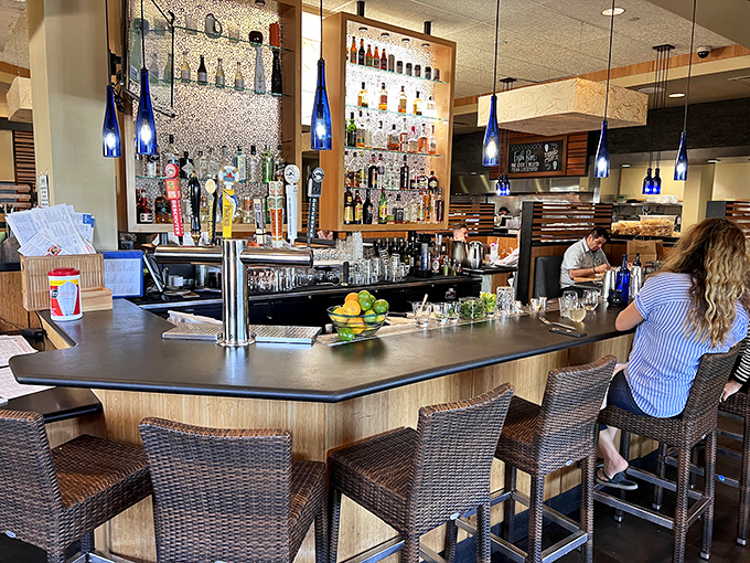 The bar at Pacific Catch&mdash;where blue bottles glow like ocean treasures and cocktail magic happens. Your next great conversation is just a barstool away.