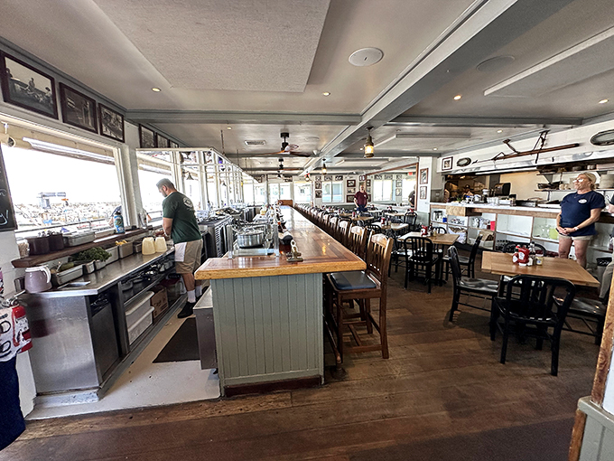 The bar stretches like a runway for seafood dreams, where bartenders orchestrate liquid happiness and harbor views come standard with every drink.