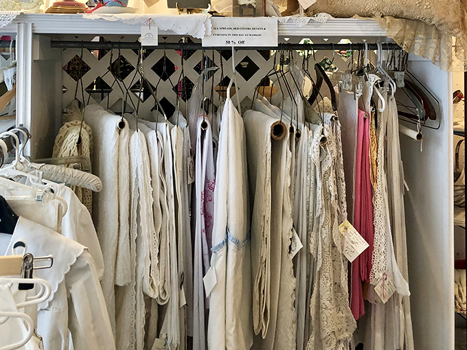 Vintage linens and delicate garments hanging like ghosts of fashion past. Each piece whispers tales of garden parties and afternoon teas.
