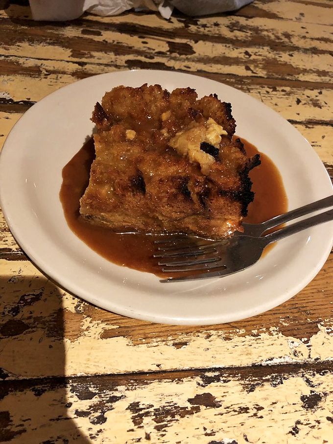 Bread pudding swimming in caramel sauce—the kind of dessert that makes you consider licking the plate in public.