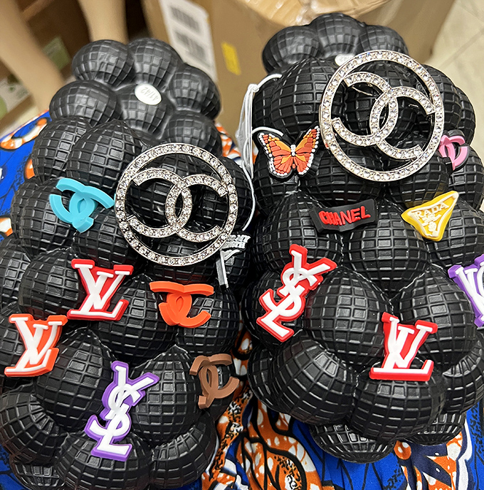 Designer-inspired accessories with logos that would make trademark attorneys weep. Fashion's democratization happens one decorative sphere at a time.