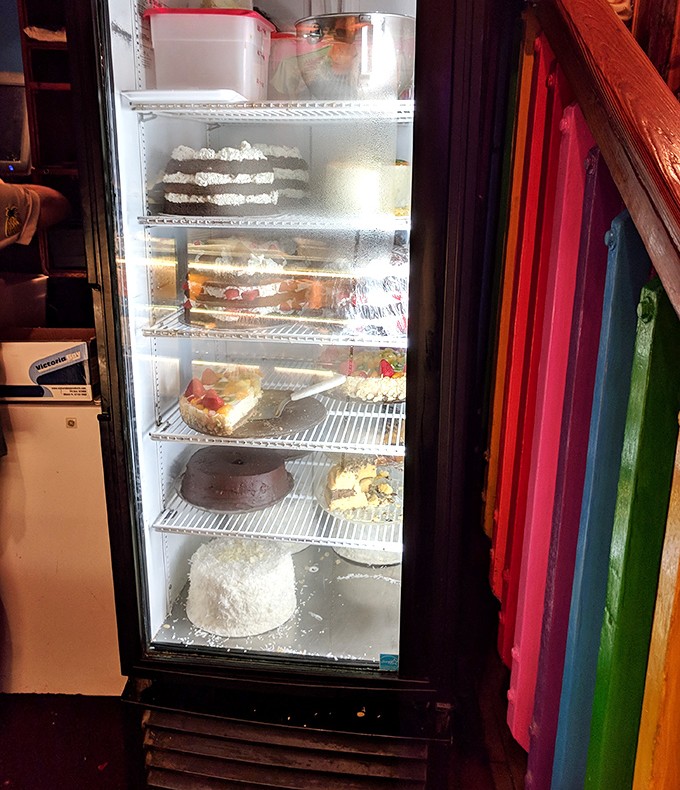 The cake display case stands like a temple to sugar, each layer visible through glass like edible architecture.