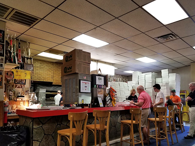 Behind that counter, pizza artisans perform their craft with the quiet confidence that comes from decades of perfecting the same beloved recipes.