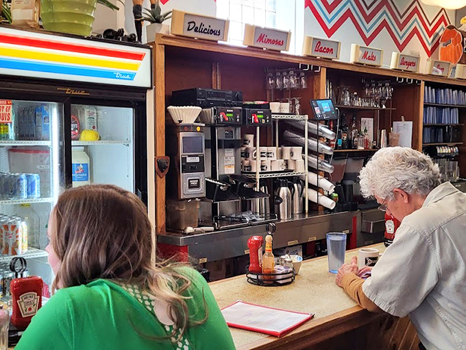 At the counter, coffee magic happens while patrons perch like regulars in a scene that could be from any decade of American diner culture.