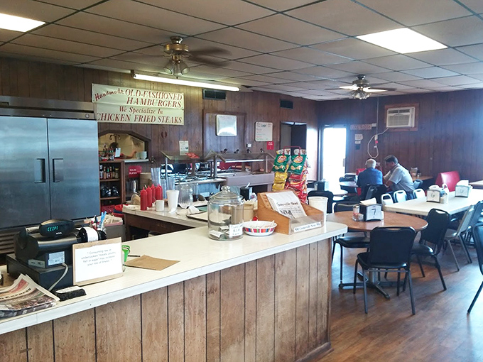 Behind the counter where magic happens&mdash;wood paneling and handwritten signs promising "OLD FASHIONED HAMBURGERS" that deliver on every syllable.