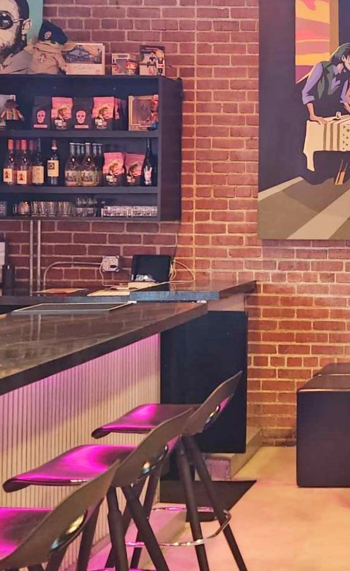 The bar area blends industrial edge with artistic flair&mdash;exposed brick, pink lighting, and artwork that reminds you this is no ordinary coffee stop.
