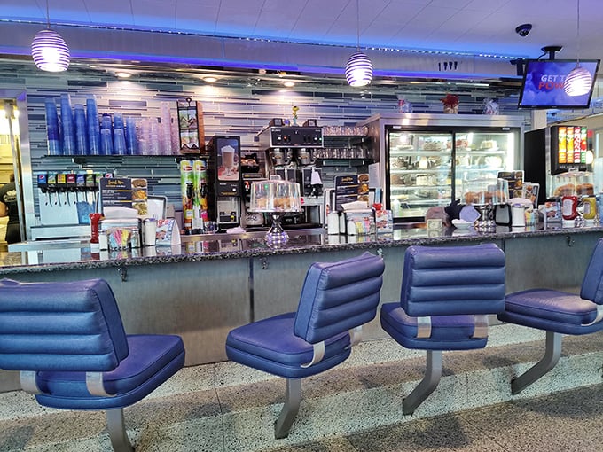 The counter gleams under blue lighting, with swivel seats that invite you to spin slightly while contemplating your dessert options.