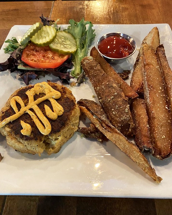 This crab cake doesn't just sit on the plate—it commands attention with its golden crust and perfect companions of fresh veggies and seasoned fries.