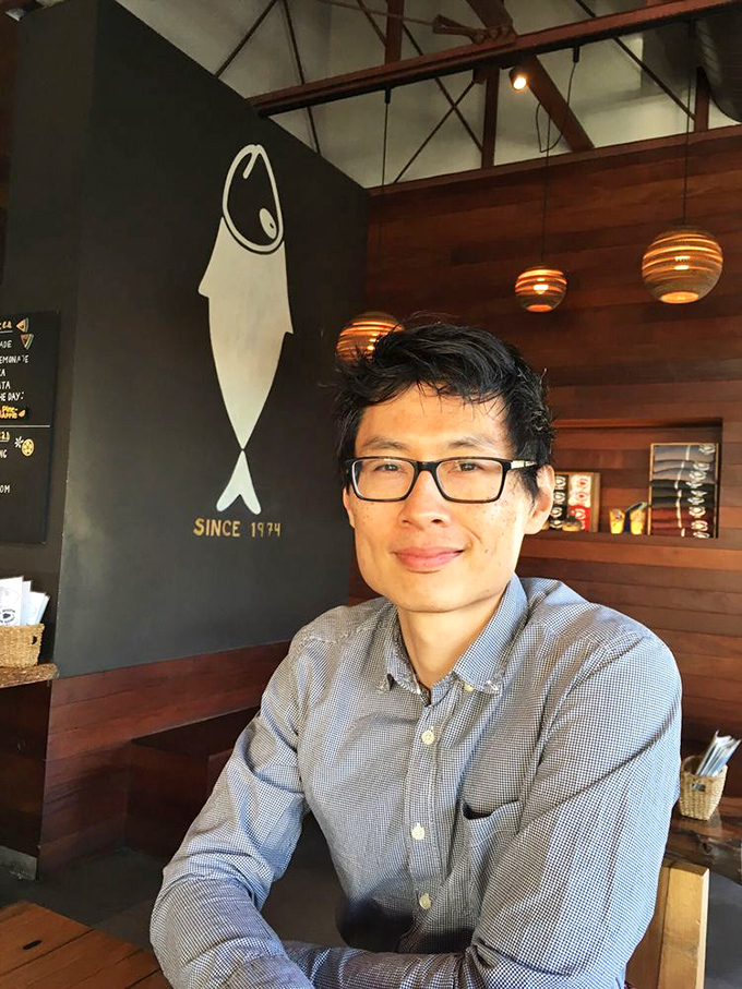A person enjoying the warm wooden interior with the iconic fish silhouette behind them&mdash;this is the face of seafood satisfaction.