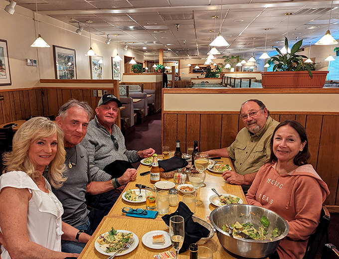 Happy diners gathered around a table of plenty – the universal language of shared meals transcending all differences.