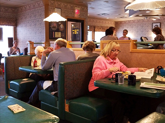 The dining room hums with the satisfied murmurs of regulars who've found their breakfast home. Green booths cradle conversations as essential as the coffee.