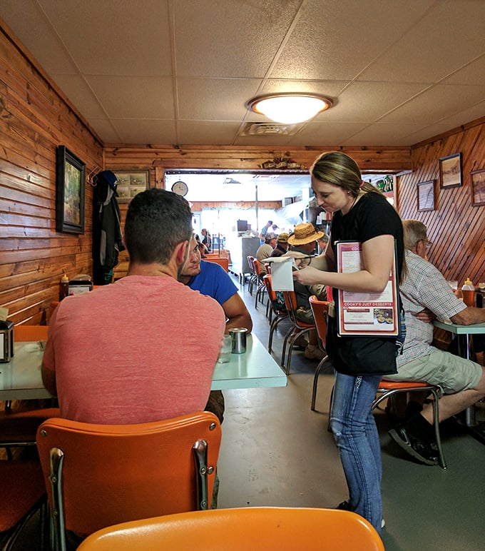 The timeless dance of server and customer plays out amid wood-paneled walls—a ritual as American as the pie in the display case.