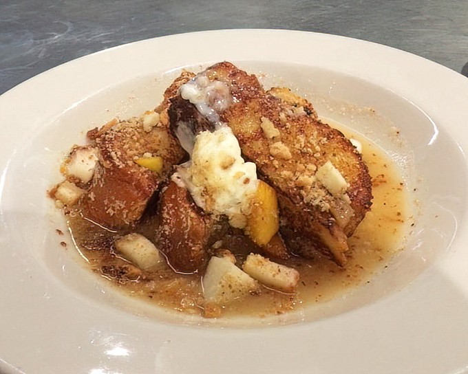 French toast that transcends ordinary breakfast boundaries. Golden-brown challah soaking in sweet syrup with fresh fruit standing by&mdash;morning decadence at its finest.