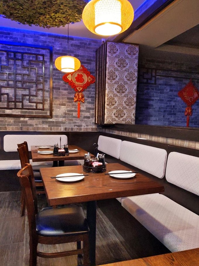 Booth seating with traditional Chinese lanterns overhead creates intimate dining spaces. It's like your own private dumpling party.