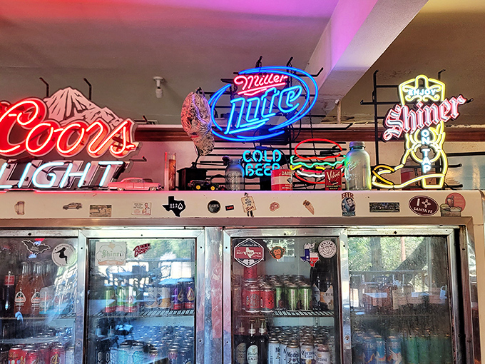 Beer signs illuminate the interior like neon beacons of hope for the thirsty traveler. The refrigerator's contents promise cold comfort after a long, dusty drive.