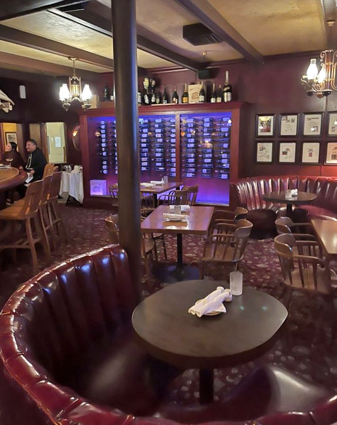 Wine bottles glow blue behind glass, creating a sophisticated backdrop for intimate conversations and celebratory toasts. 