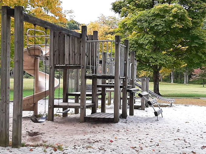 The playground stands ready for tiny adventurers, its wooden structures offering the perfect excuse for parents to say "go burn off some energy!"