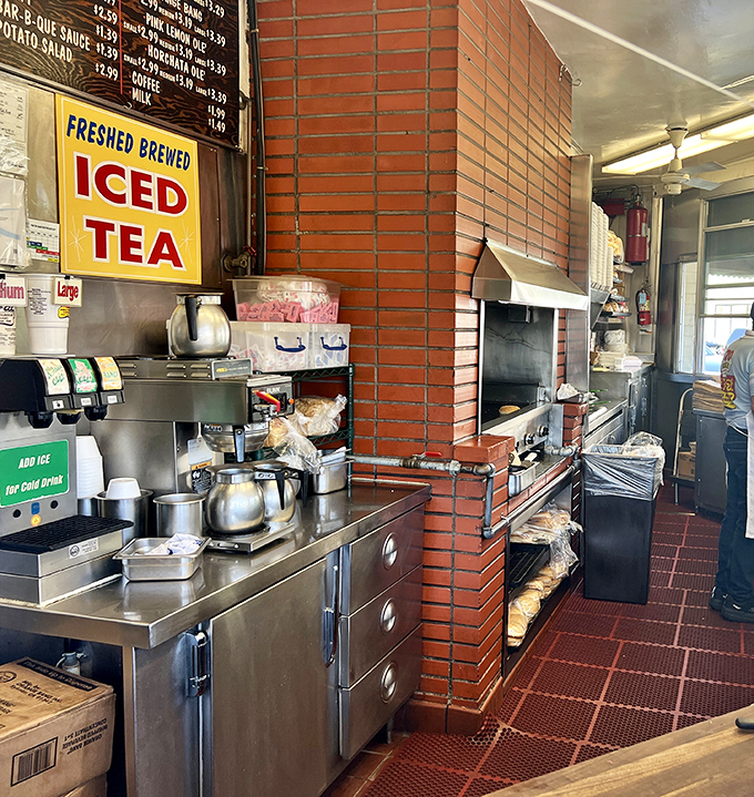 The kitchen view reveals the no-nonsense, brick-lined heart of the operation where pastrami magic happens without unnecessary frills.
