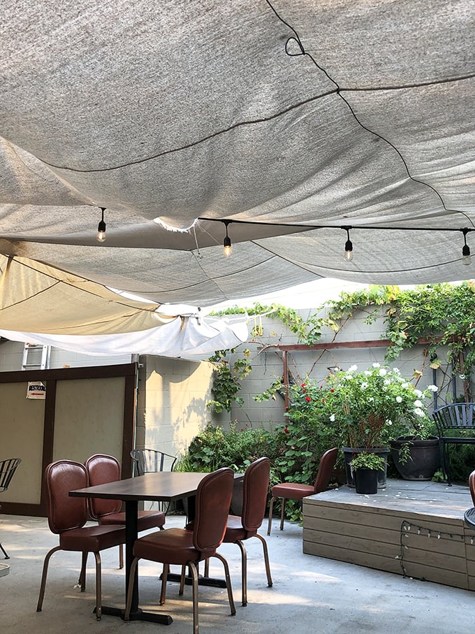 The hidden patio oasis offers al fresco dining under fabric canopies. A secret garden escape in the heart of Gilroy.