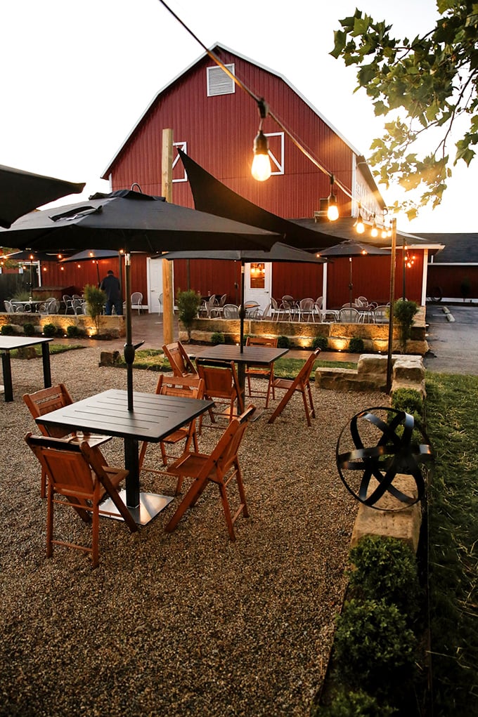 As the sun sets, the outdoor patio transforms into a magical space where string lights twinkle above tables and conversation flows as easily as the wine.