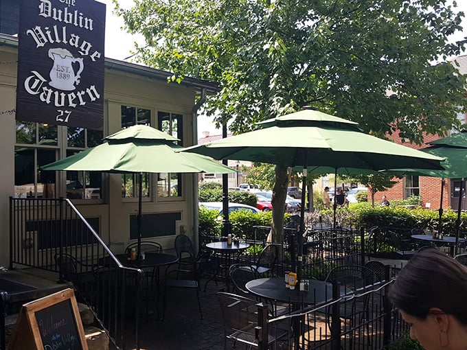 The outdoor patio offers a perfect summer escape, with green umbrellas providing shade for those who prefer their pints with fresh air.