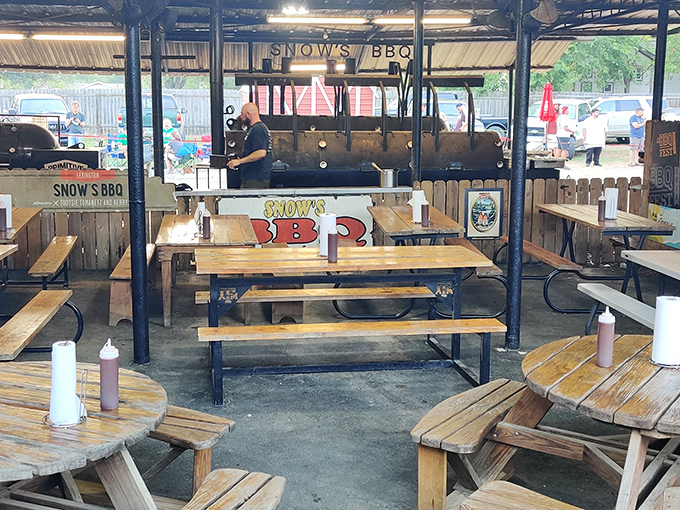 The outdoor pit area &ndash; barbecue's sacred temple where smoke rises like prayers and picnic tables await the faithful with rustic simplicity.