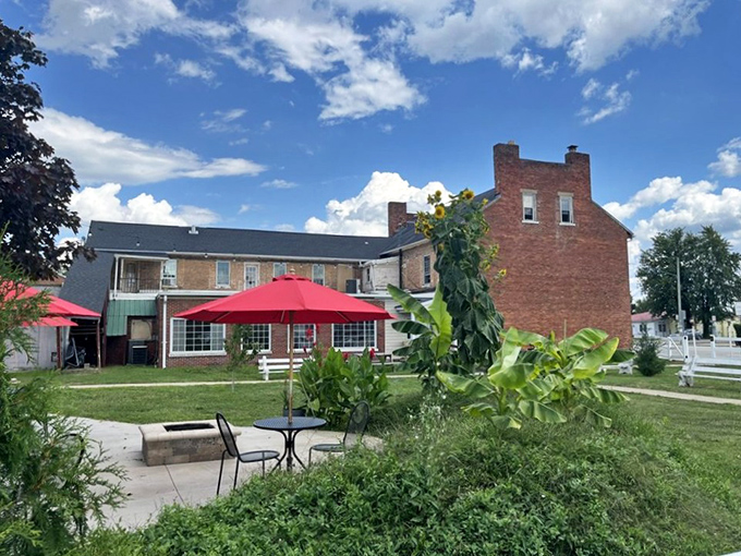 The back patio offers a garden view with red umbrellas providing shade for those who prefer their history with a side of fresh air.