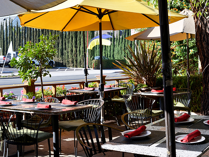 Under yellow umbrellas, the patio offers a tranquil breakfast escape with cypress trees standing guard against the outside world.
