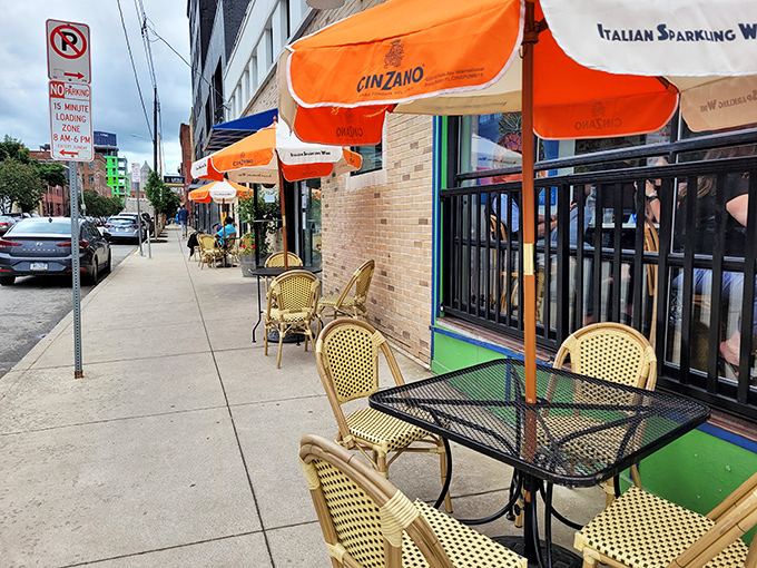 Cinzano umbrellas create little islands of European charm on the sidewalk, where people-watching becomes an appetizer course.
