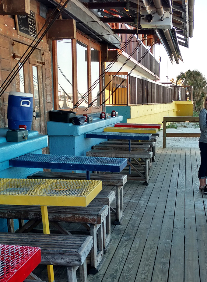 Technicolor tables line the weathered deck like a beach party waiting to happen, where every seat comes with a side of sea breeze.