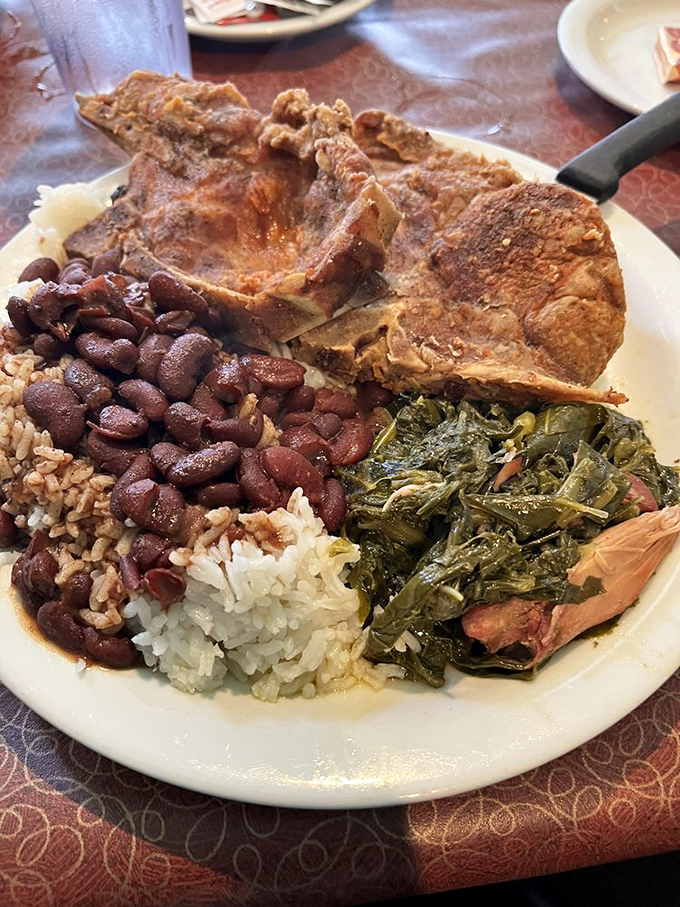 Soul food royalty on a plate&mdash;pork chop, collard greens, and red beans over rice that taste like they've been simmering since yesterday.