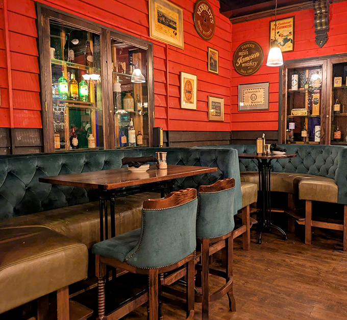 Rich red walls, emerald seating, and wooden accents create a space that feels both sophisticated and completely unpretentious.