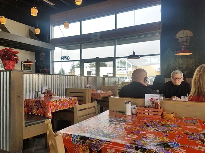 The dining area where morning conversations bloom over coffee refills and the orange floral tablecloths somehow make everything taste better.