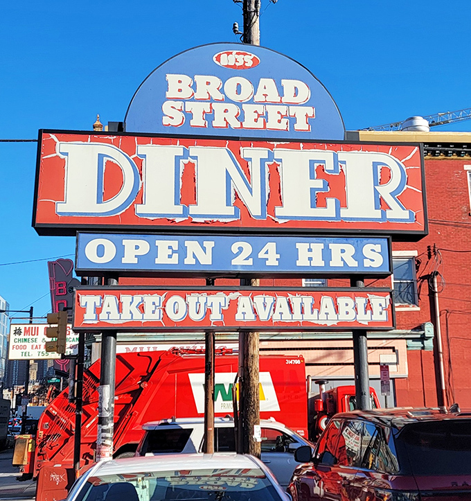 The vibrant red and blue signage announces "OPEN 24 HRS" to night owls and early birds alike&mdash;a democratic institution serving breakfast democracy to all.
