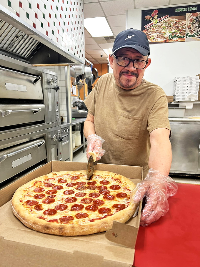 The pizza maestro at work &ndash; where every pepperoni placement is deliberate and years of experience show in each confident slice of the cutter.